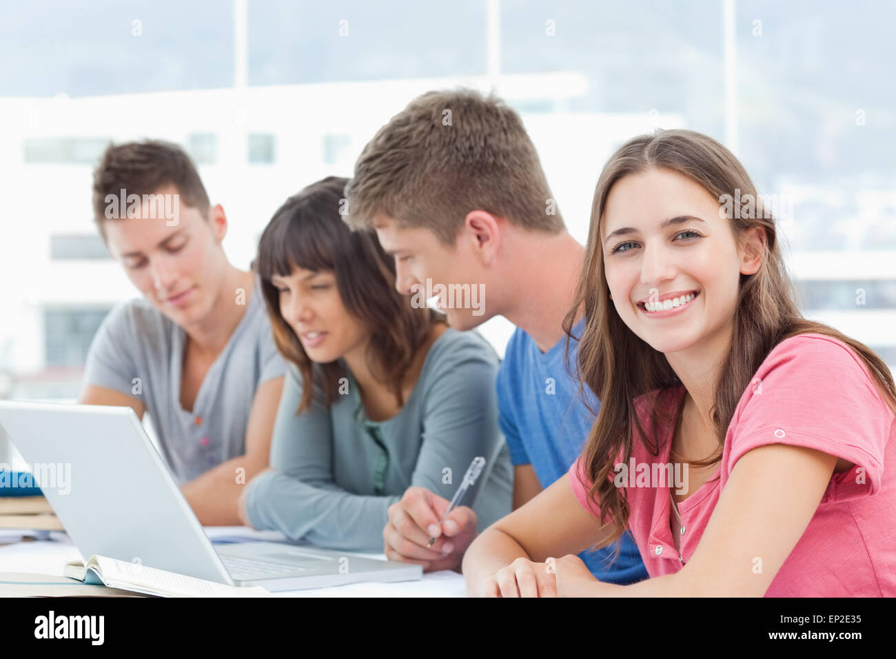 Three students look into the laptop as the fourth student looks at the ...