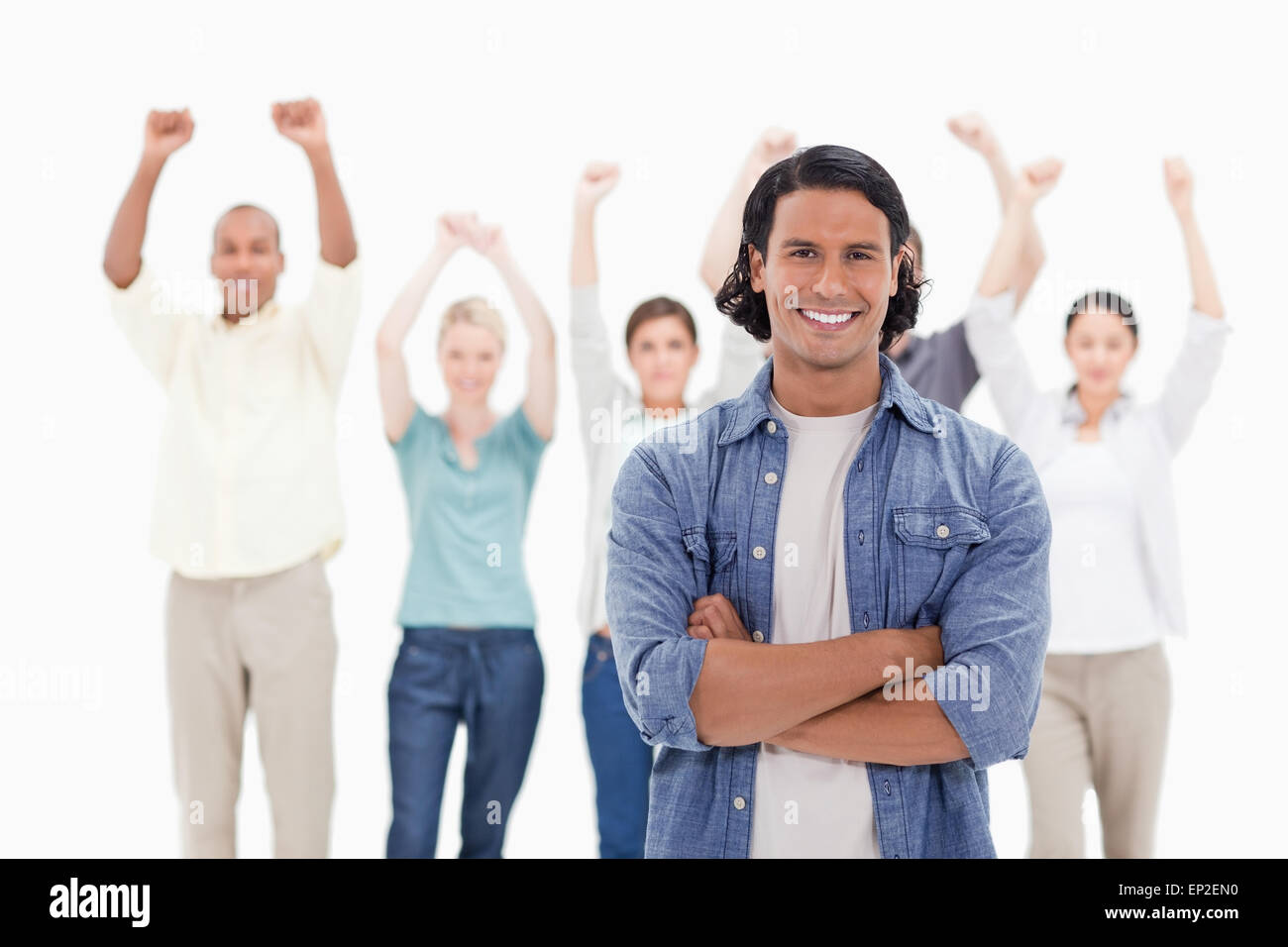 Close-up of a man crossing his arms with people raising their arms ...