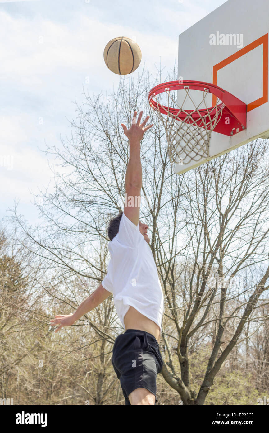 Young man doing basketball trick shots as he leaps through the air ...