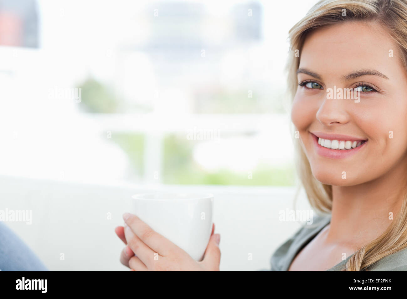 Woman smiling, looking forward and holding up a mug in hands Stock ...