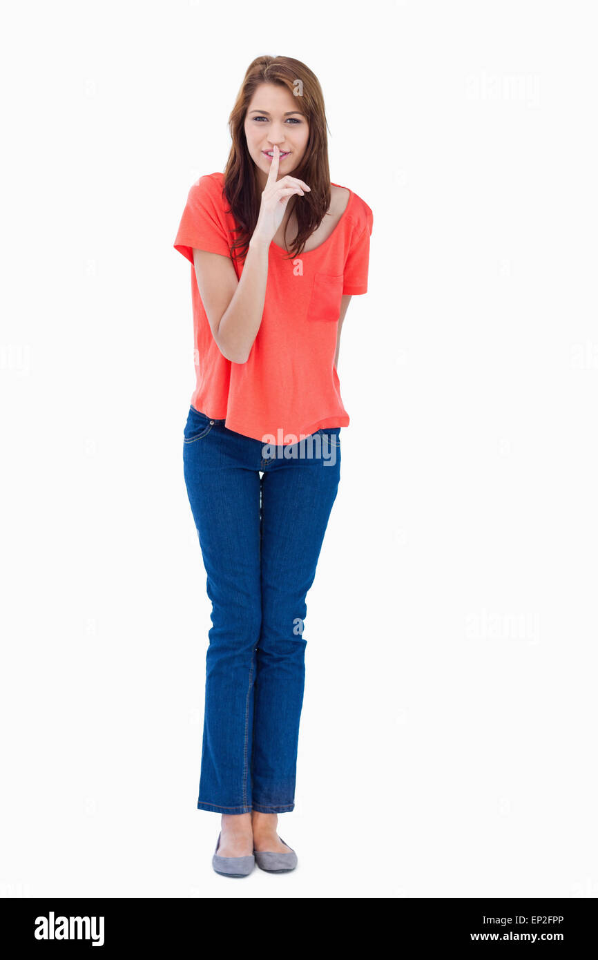 Young woman standing up while showing a quiet gesture Stock Photo - Alamy