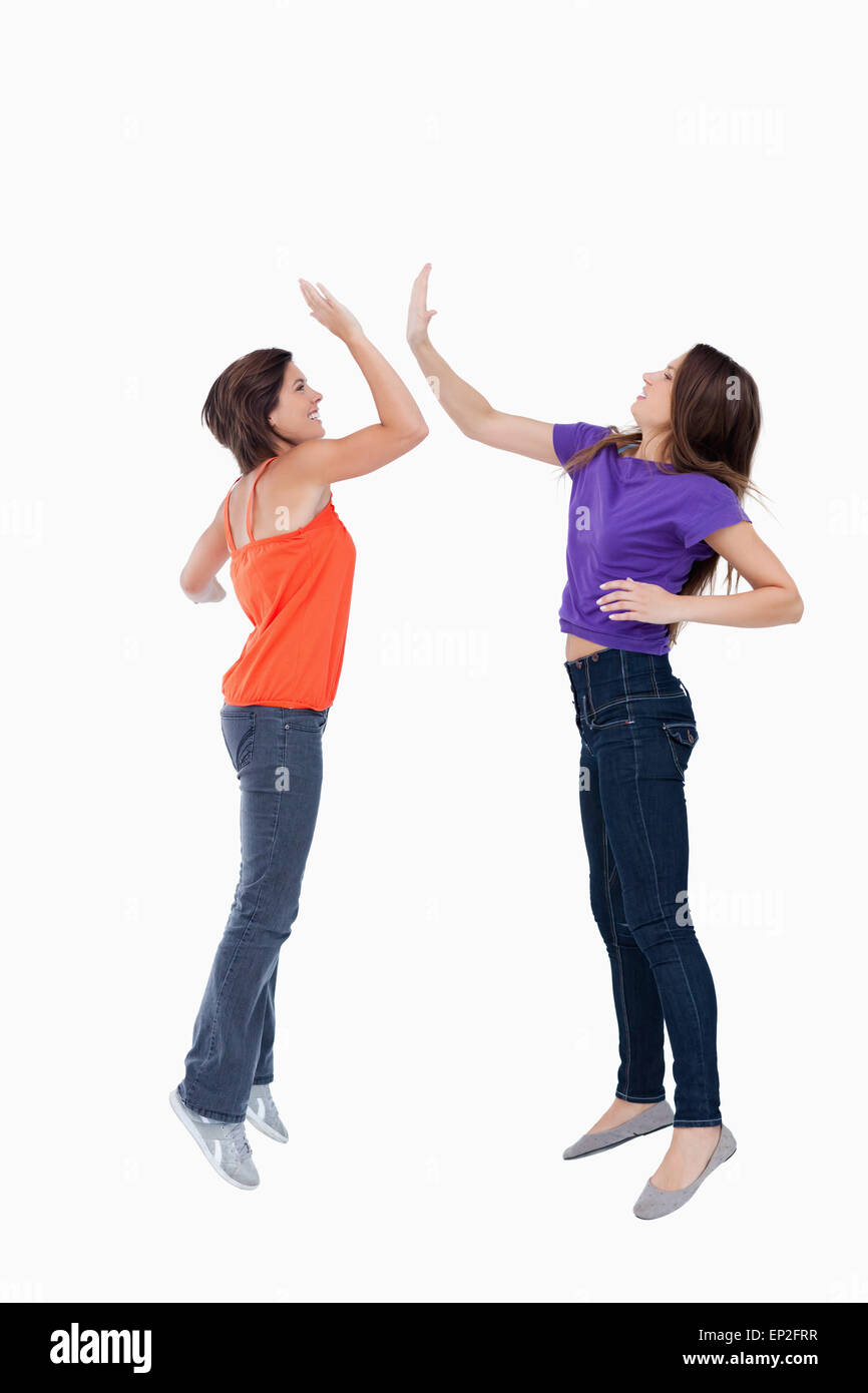Teenagers jumping while giving each other a high-five Stock Photo - Alamy