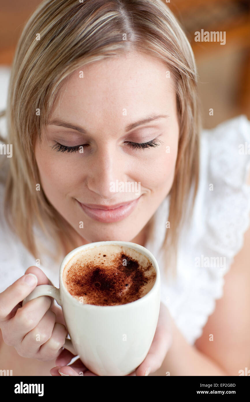 Attractive woman drinking a coffee sitting on a sofa Stock Photo - Alamy