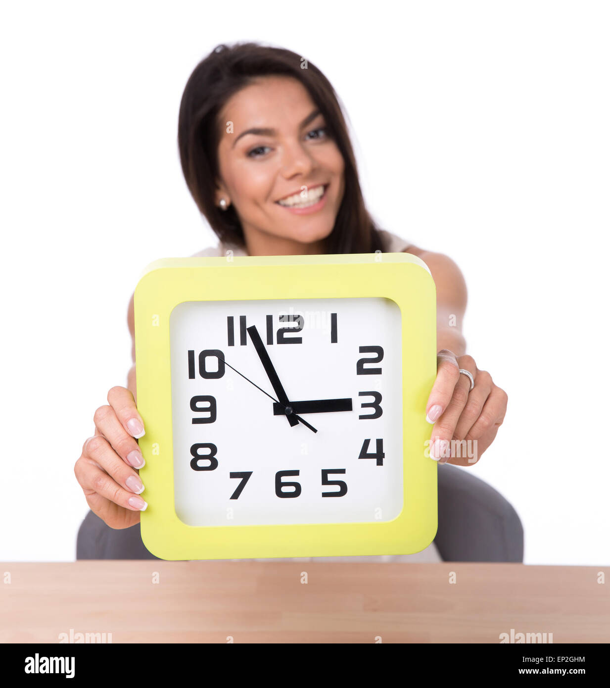 Happy businesswoman sitting at the table and showing big clock over ...