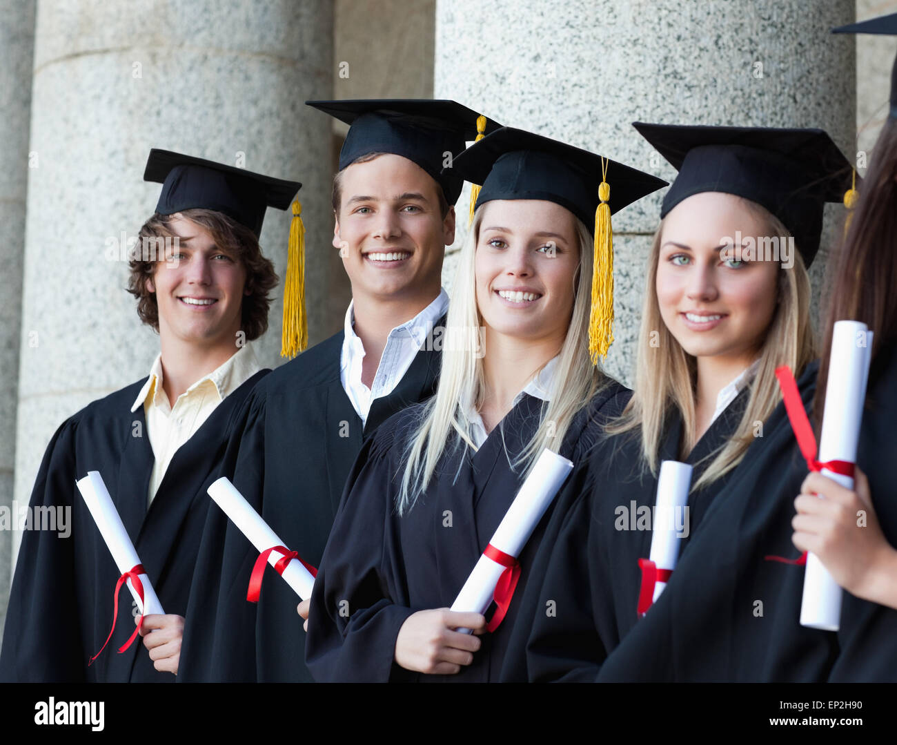 Portrait of smiling graduates posing in single line Stock Photo - Alamy