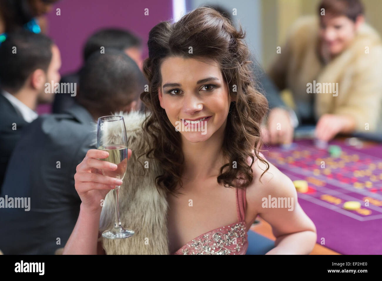 Woman smiling raising her glass at roulette table Stock Photo - Alamy