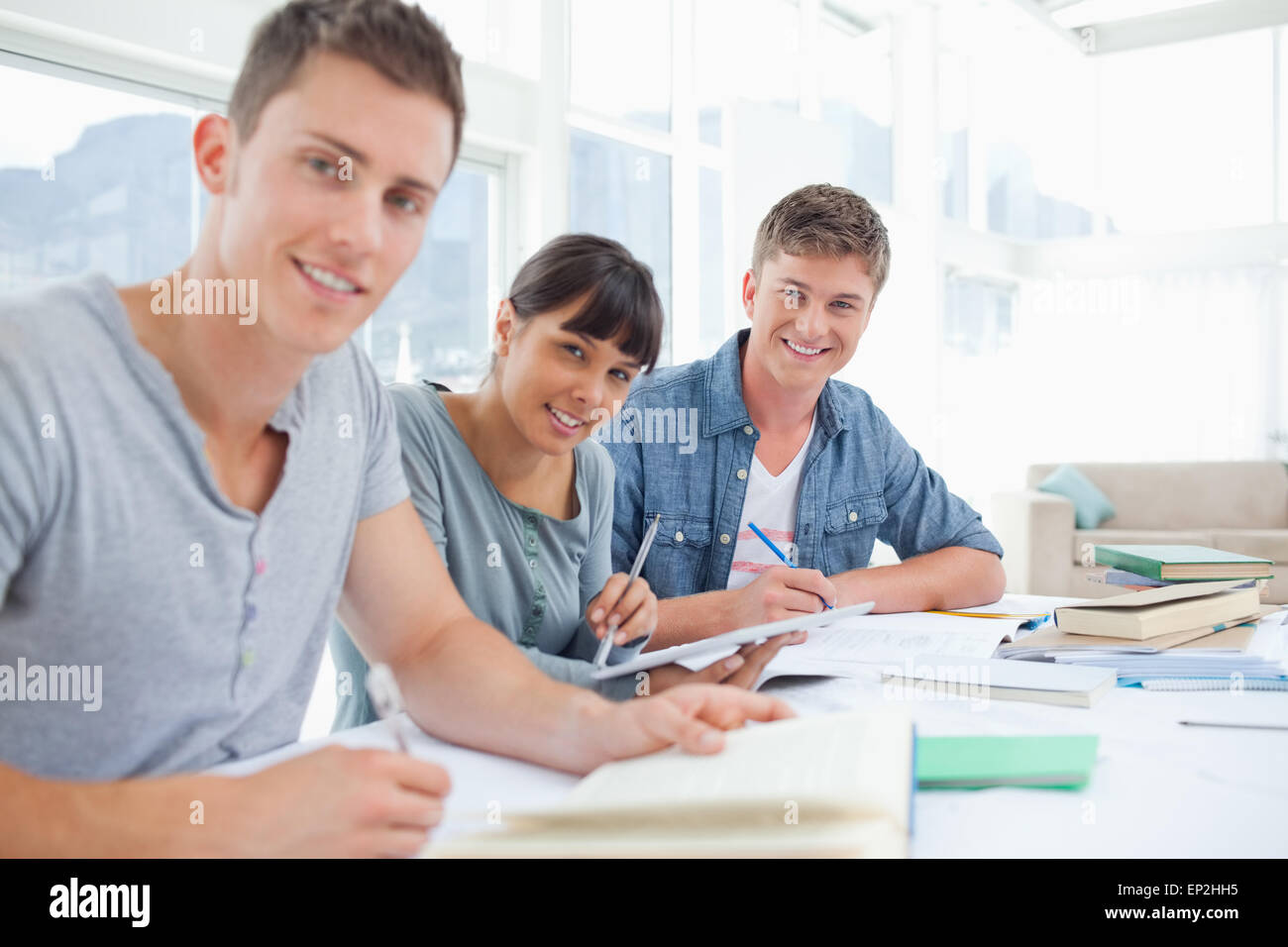 Three students sitting together as they all look into the camera Stock ...