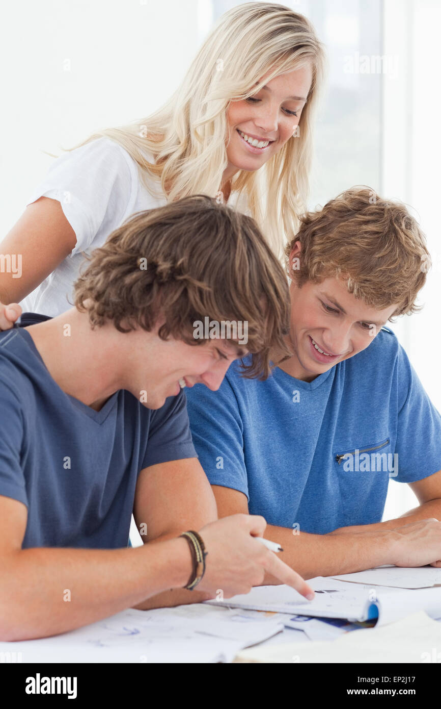 Two smiling students studying together as a girl stands overhead Stock ...