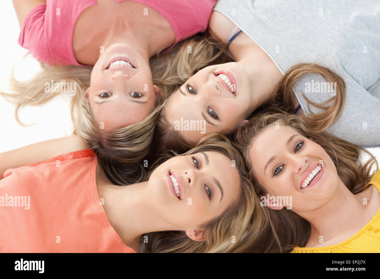 Four girls smiling as they lie on the floor together Stock Photo - Alamy