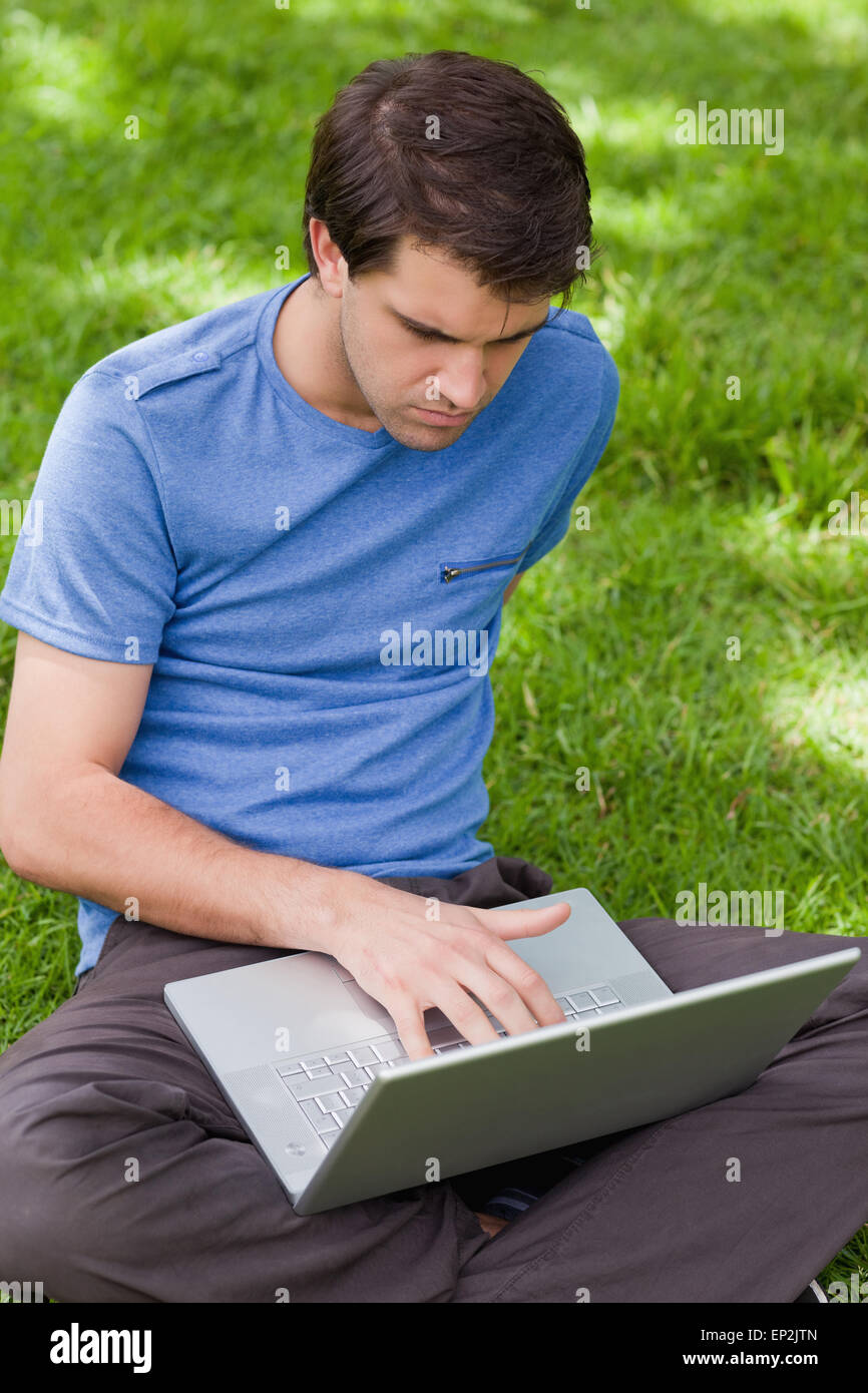 Young serious man working on his laptop while sitting in a park Stock ...