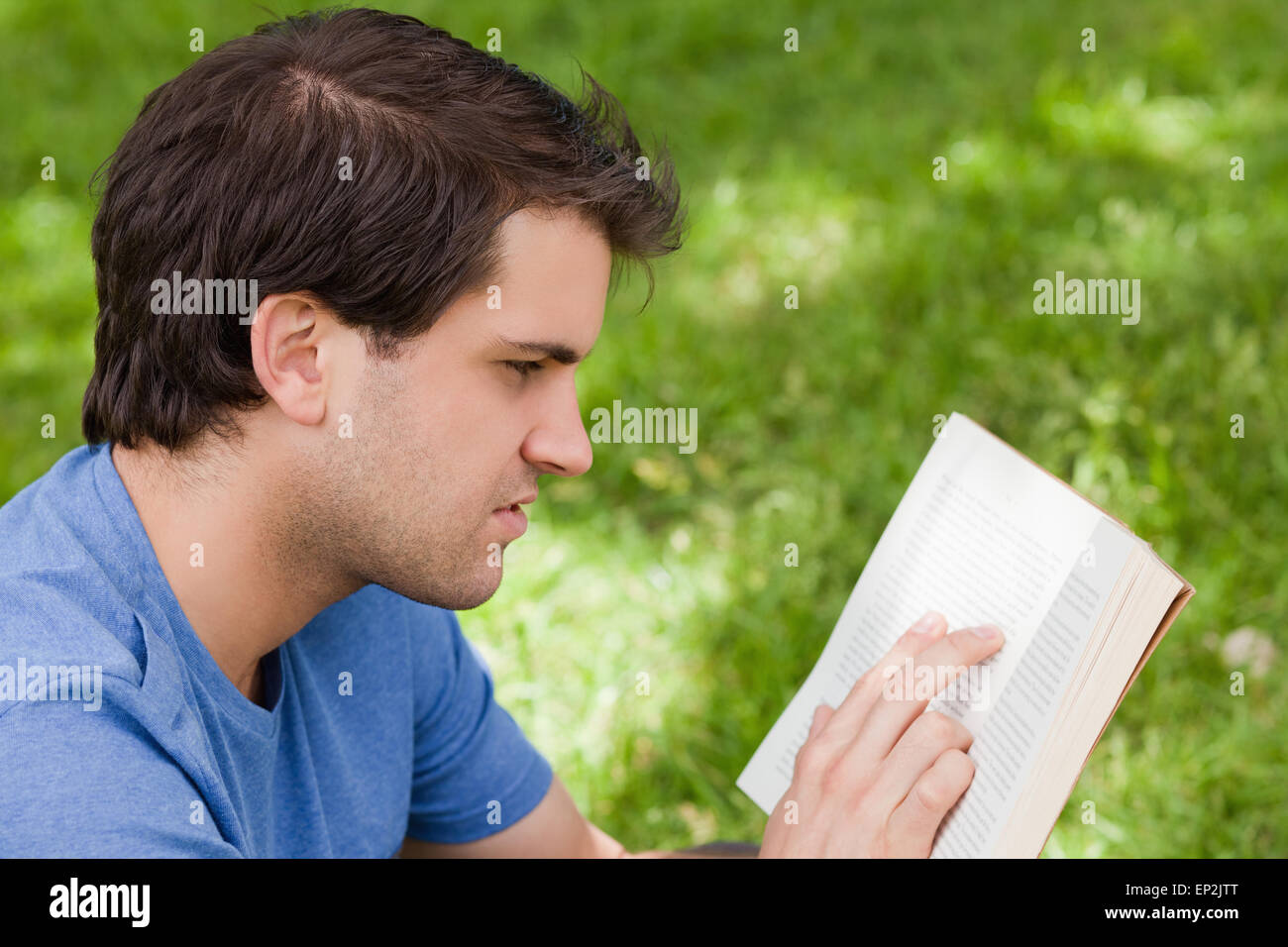 Young serious man reading a book while sitting in a park Stock Photo ...