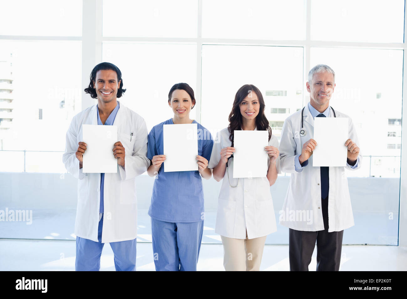 Four medical people standing upright while holding blank sheets Stock ...