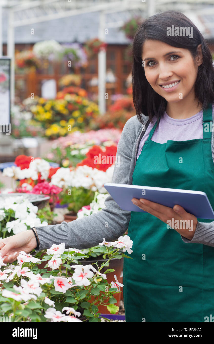 Smiling worker checking flowers in garden center Stock Photo - Alamy