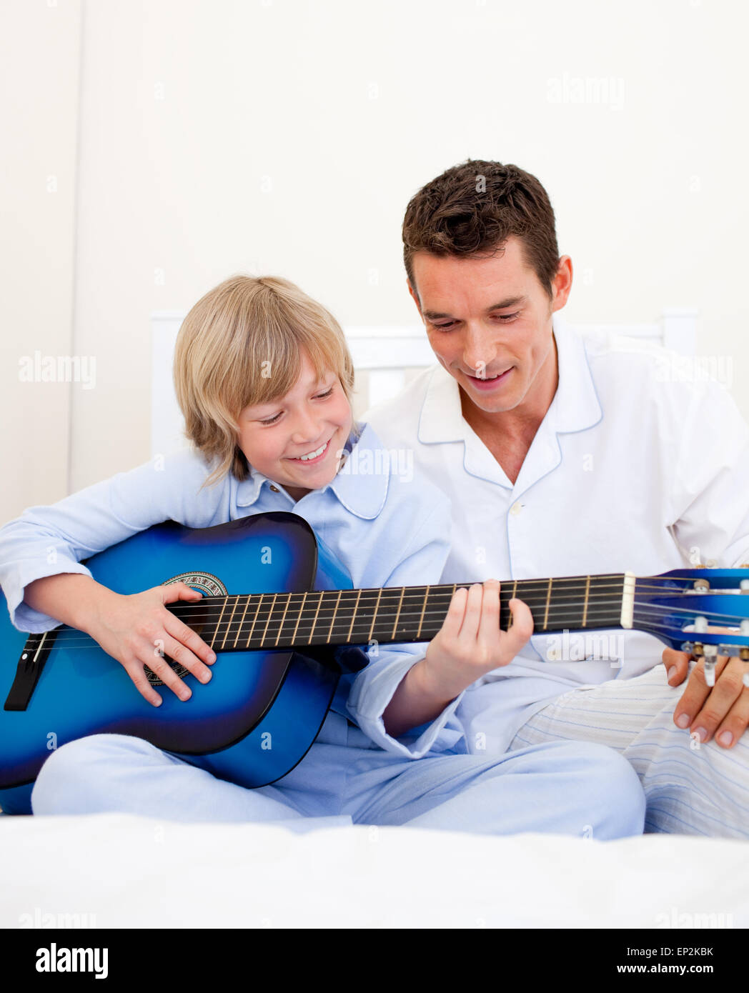 Smiling little boy playing guitar with his father Stock Photo - Alamy