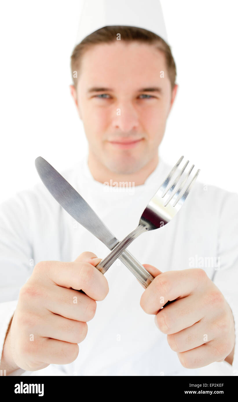 Handsome cook holding cutlery against white background Stock Photo - Alamy