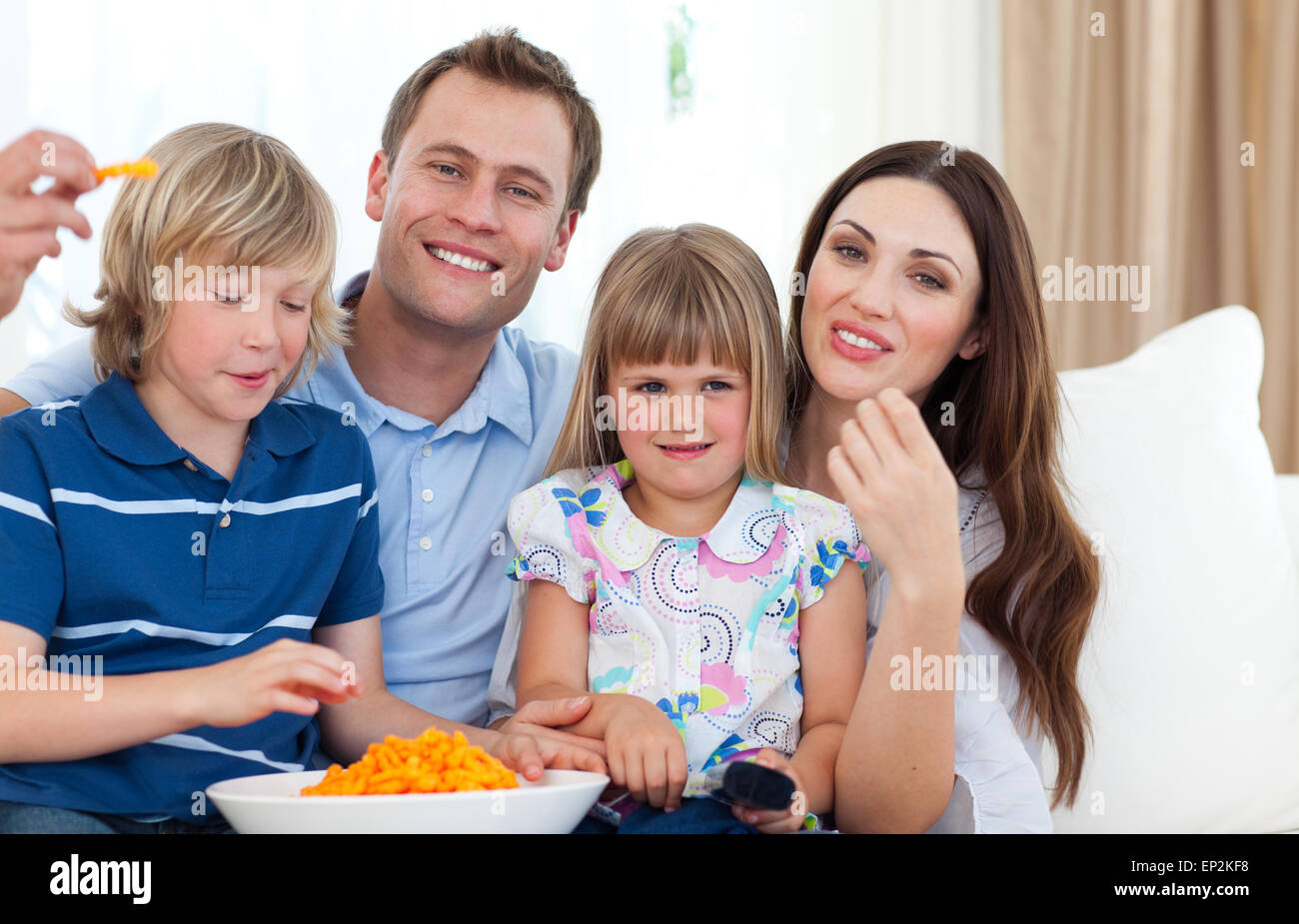 Happy family eating crisps Stock Photo - Alamy