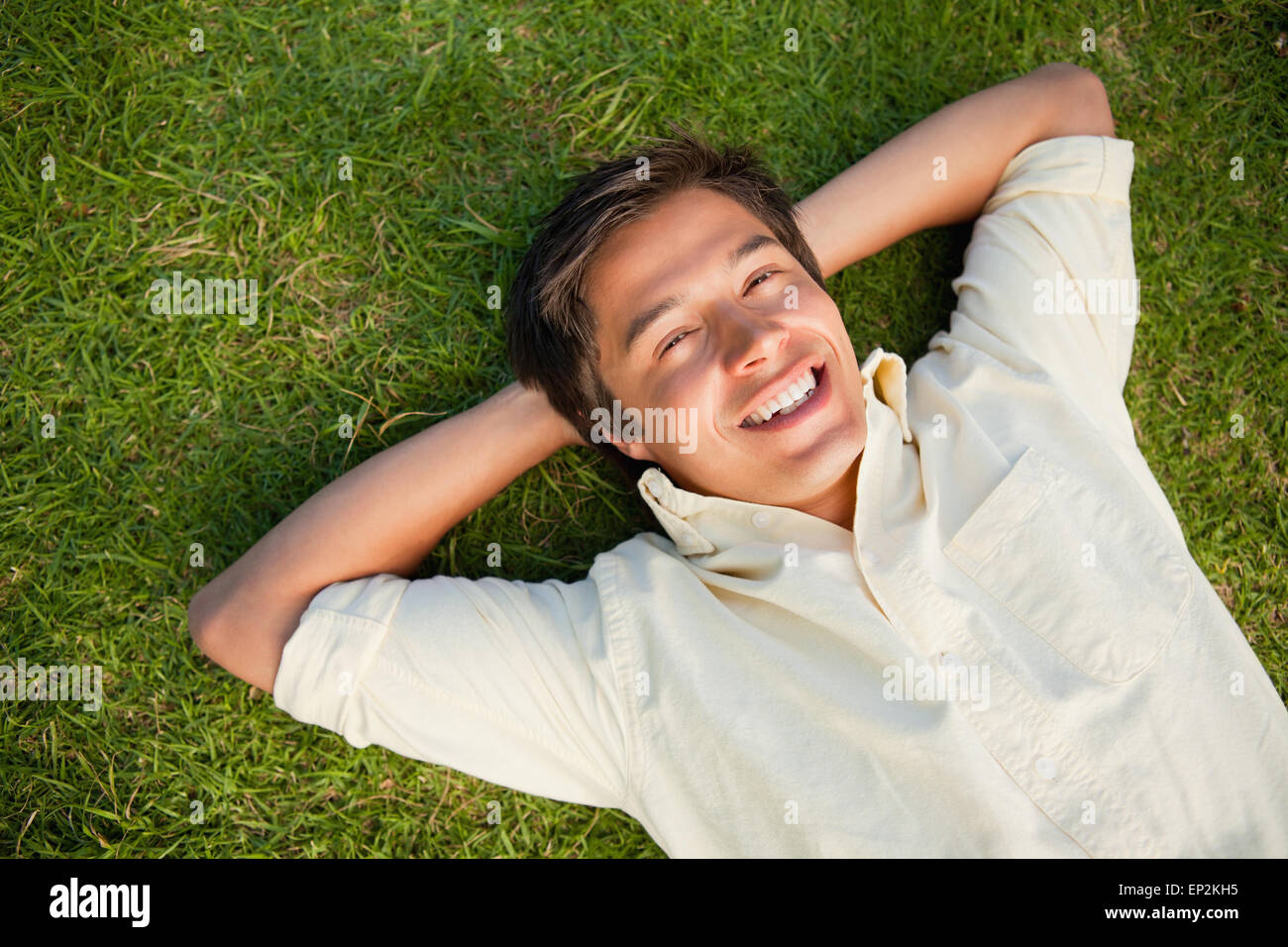 Man smiling as he lies with both hands behind his neck Stock Photo - Alamy