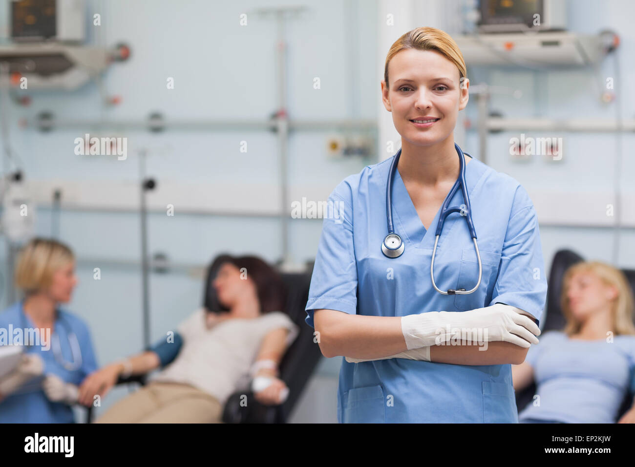 Nurse standing with arms crossed next to patients Stock Photo - Alamy