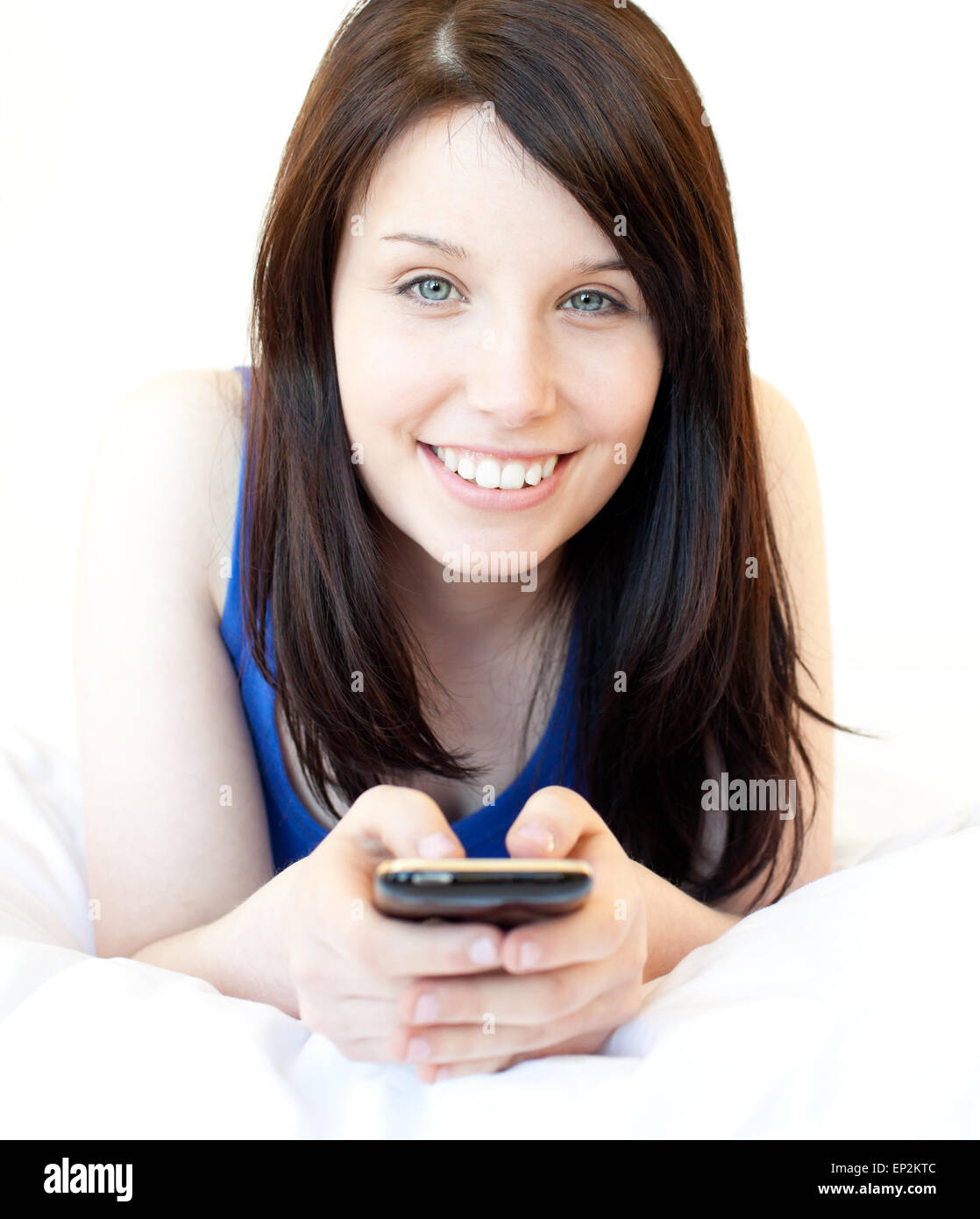 Happy young woman texting while lying on a bed Stock Photo - Alamy