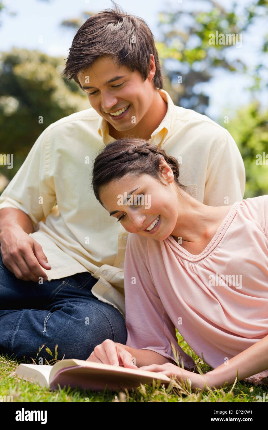 Two friends reading a book while lying down together Stock Photo - Alamy