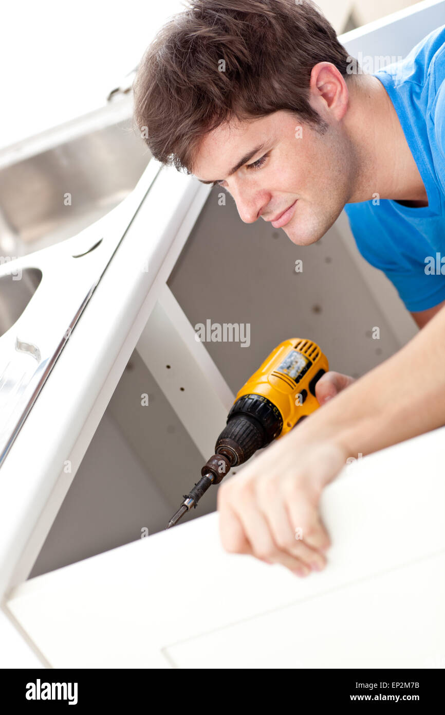 Confident man holding a drill repairing a kitchen sink Stock Photo - Alamy