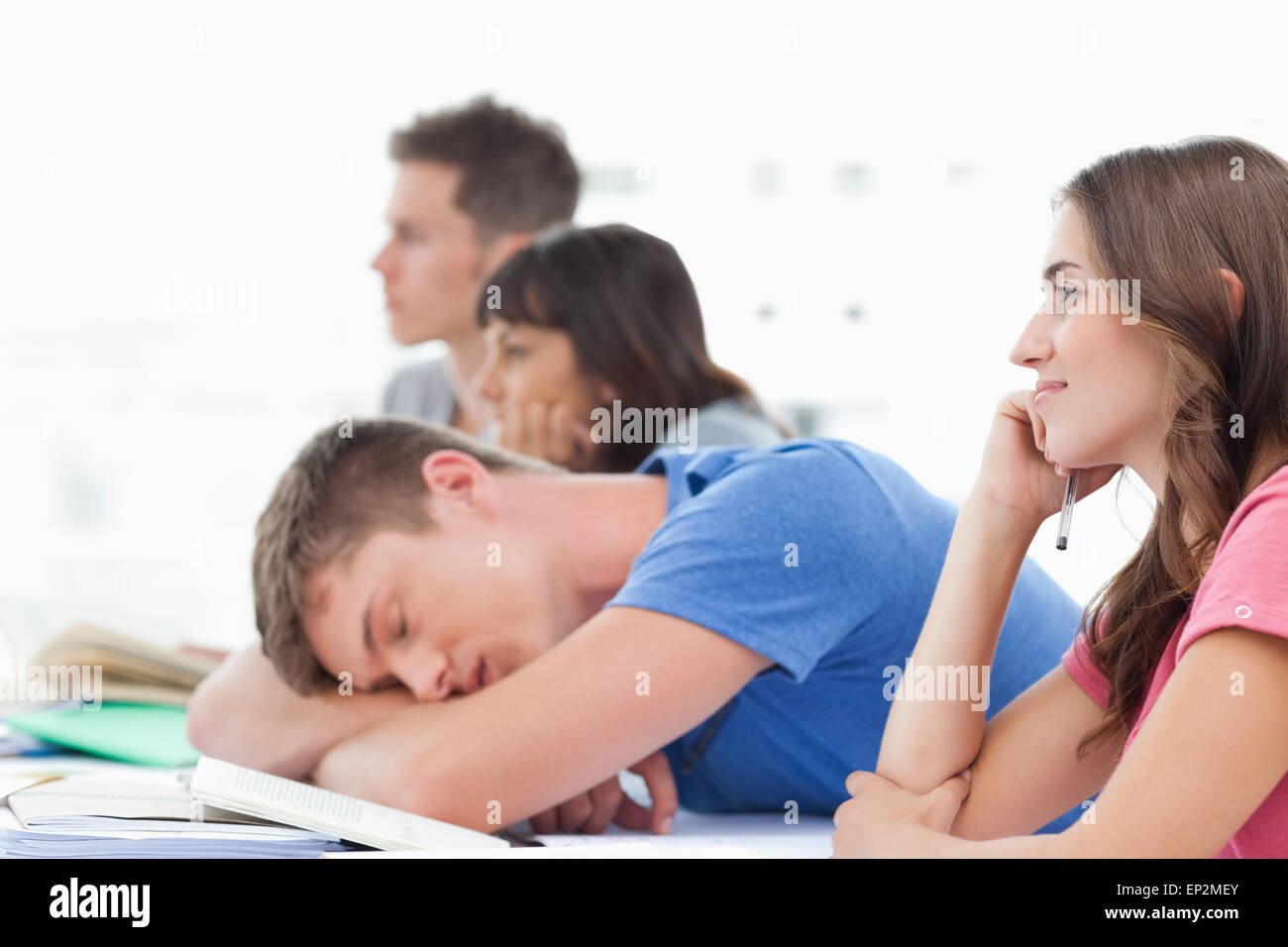 Three students listening in class with another student taking a nap ...
