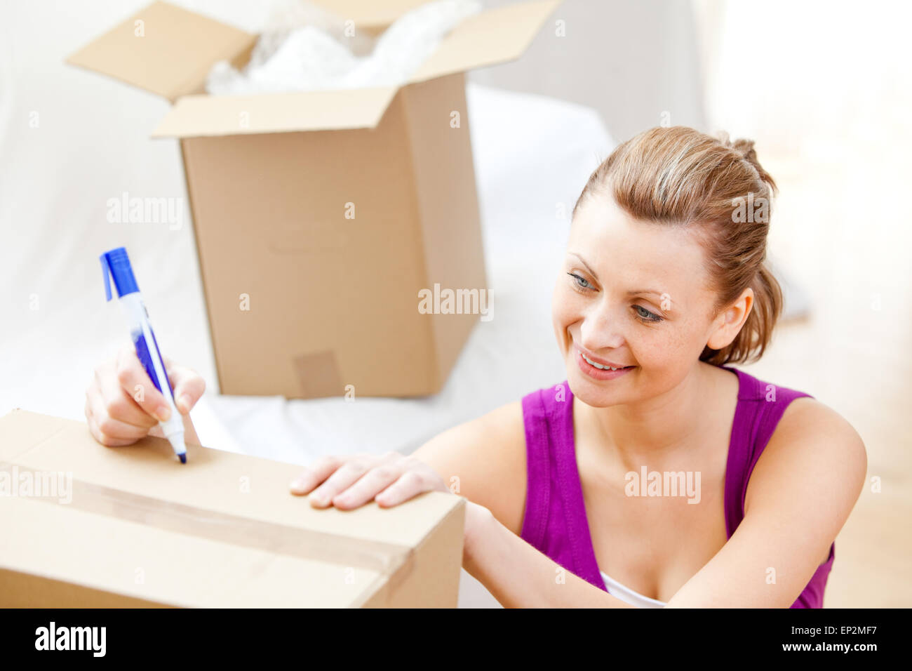 Happy woman writing on boxes using a pen Stock Photo - Alamy