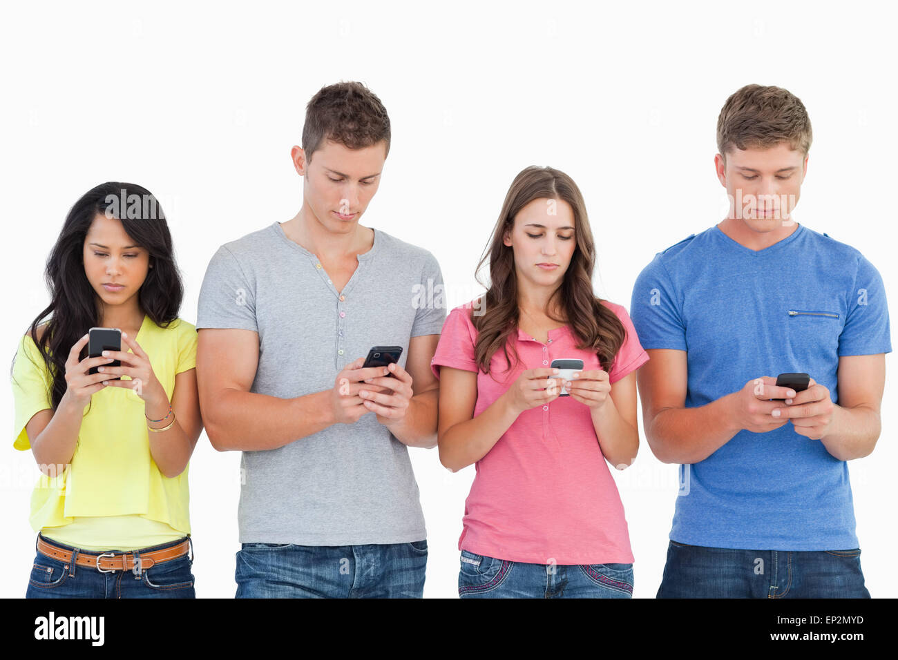 Four people standing beside each other and texting on their phones ...