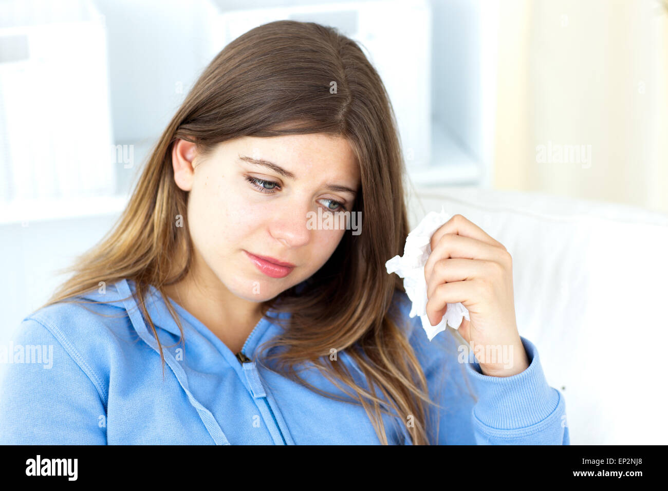 Sad young woman holding tissues sitting in the living-room Stock Photo ...