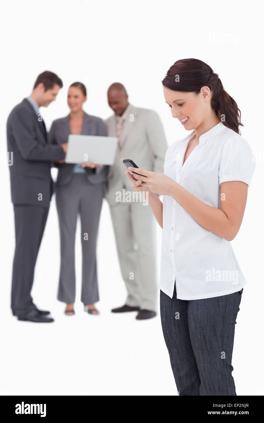 Saleswoman with mobile phone and colleagues behind her Stock Photo - Alamy