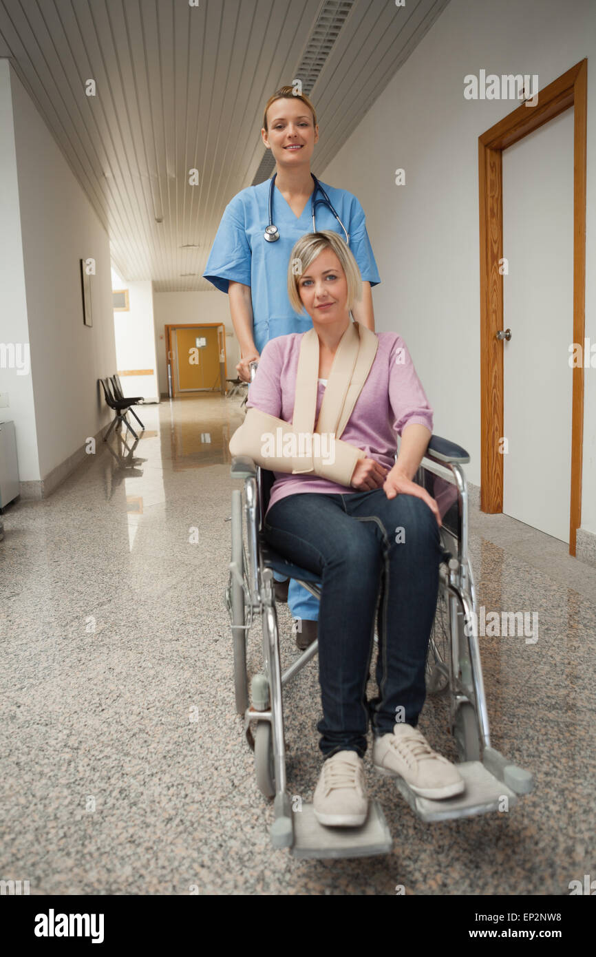 Nurse pushing wheelchair of patient with arm sling Stock Photo - Alamy