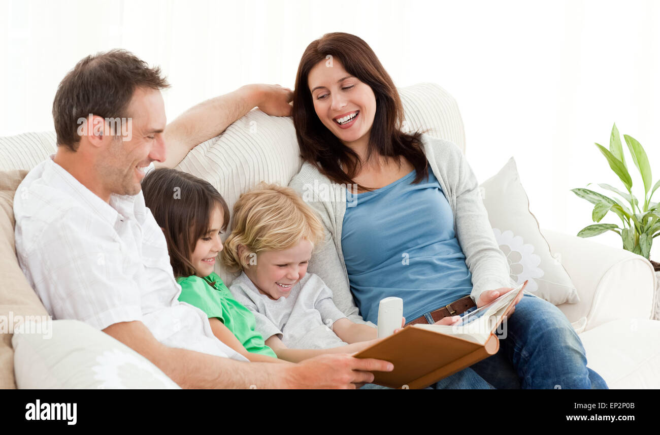 Happy parents looking at a photo album with their children Stock Photo ...