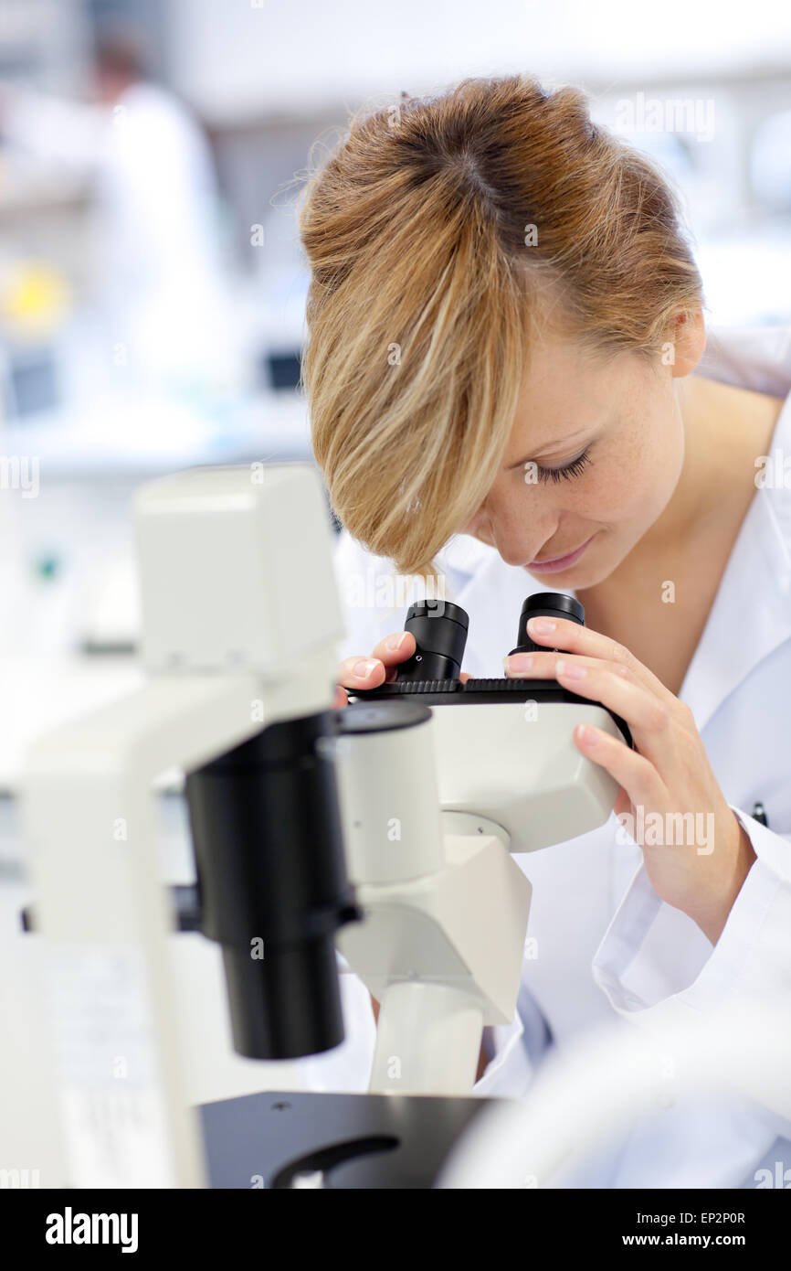Serious female scientist using a microscope Stock Photo - Alamy