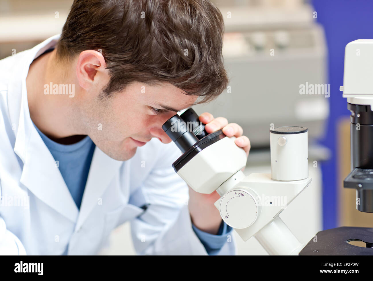 Assertive male scientist looking through a microscope Stock Photo - Alamy