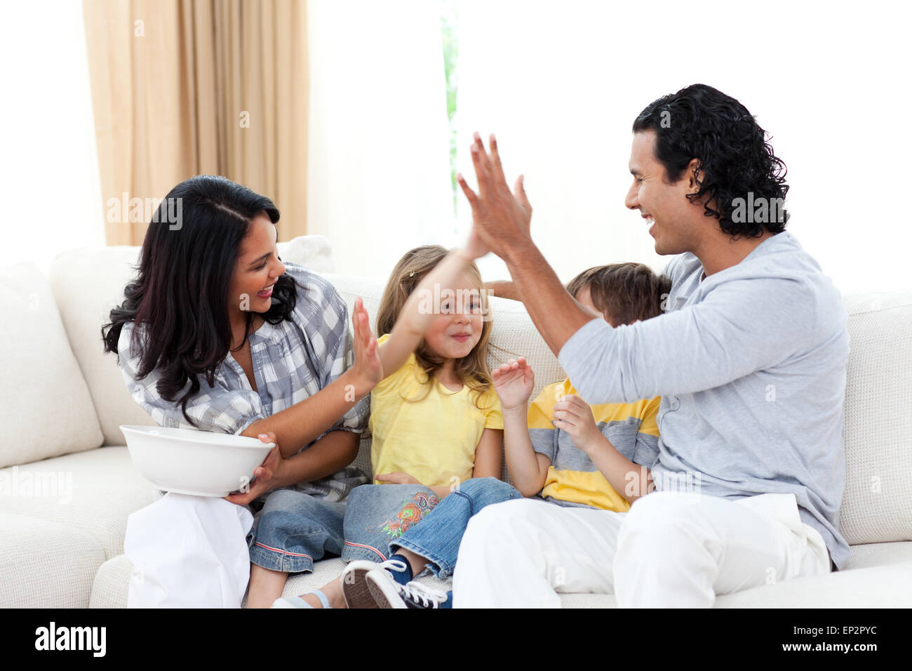 Joyful family watching TV on sofa Stock Photo - Alamy