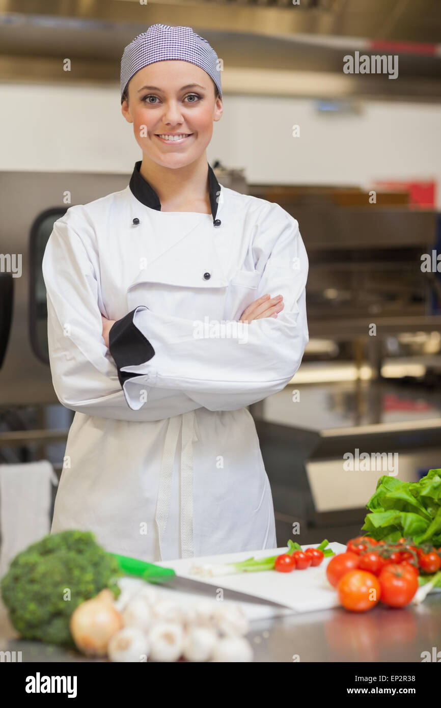 Smiling chef folding her arms beside vegetables Stock Photo - Alamy