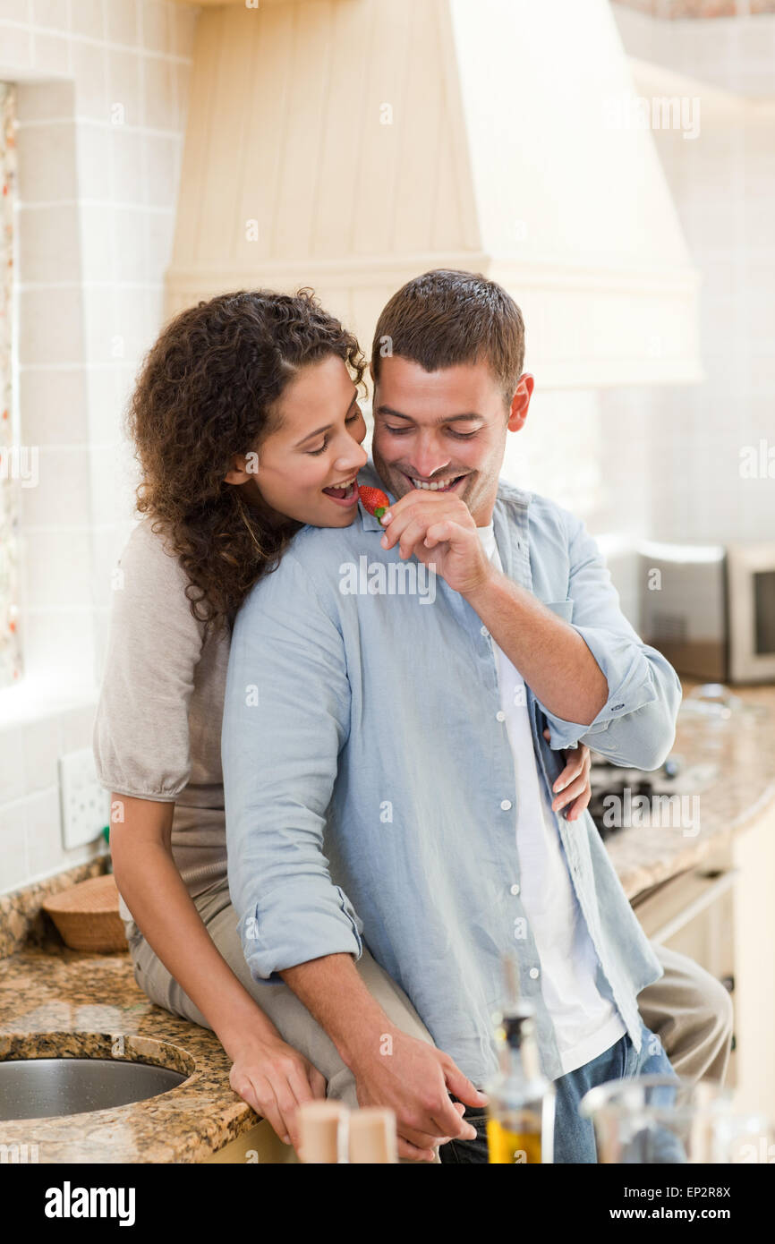 Lovers eating a strawberry in their kitchen Stock Photo - Alamy