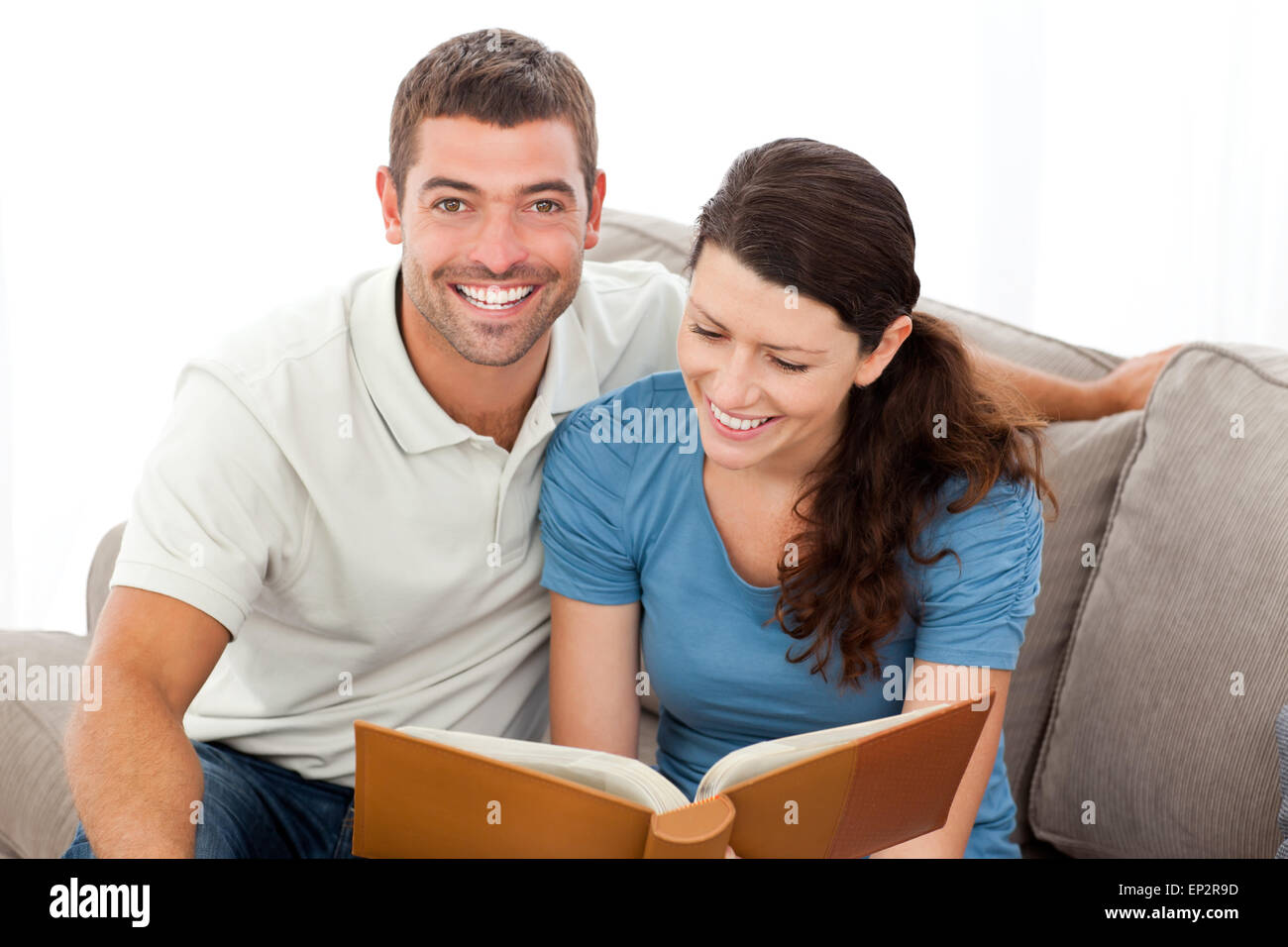 Pretty woman reading a book with her boyfriend on the sofa Stock Photo ...