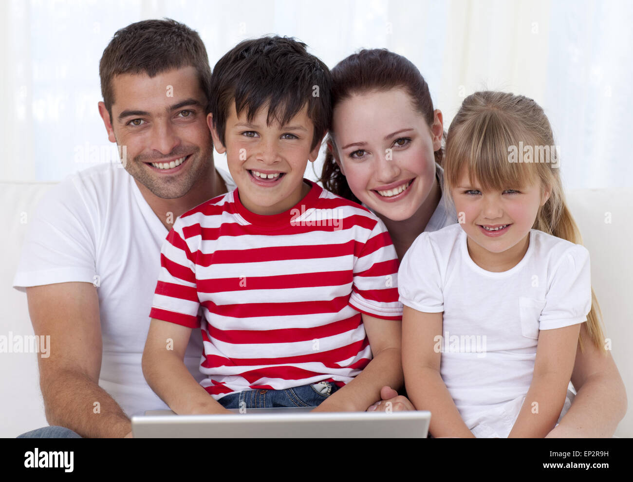 Smiling family at home using a laptop Stock Photo - Alamy