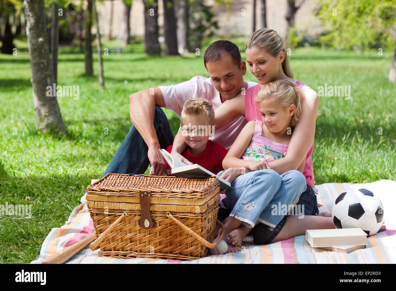 Smiling family reading while having a picnic Stock Photo - Alamy