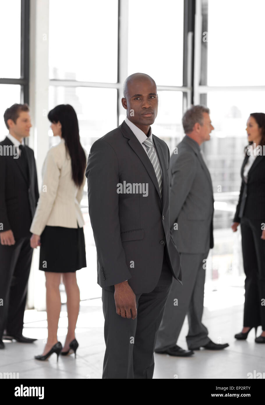 Serious business leader looking at camera in front of team Stock Photo ...