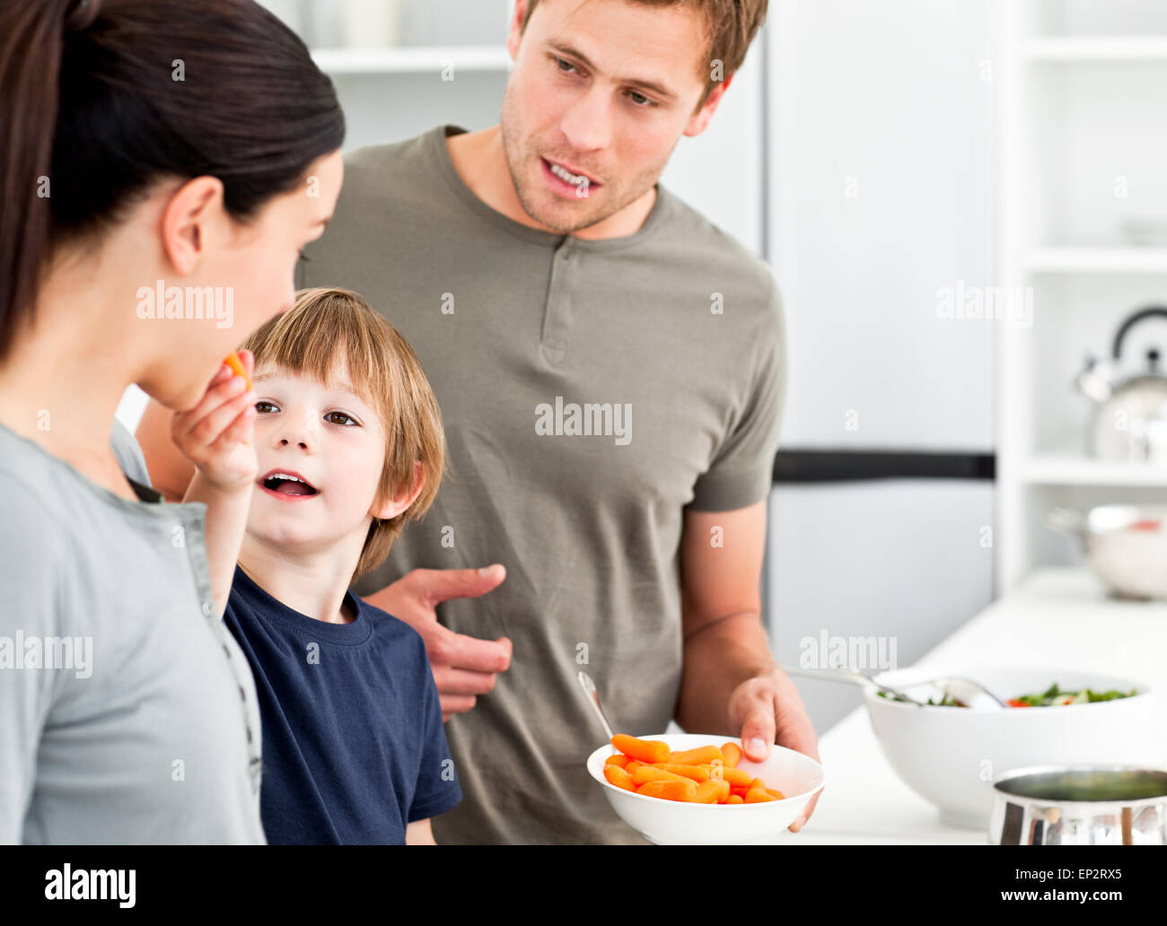 Little boy giving his mother a carrot while preparing lunch Stock Photo ...