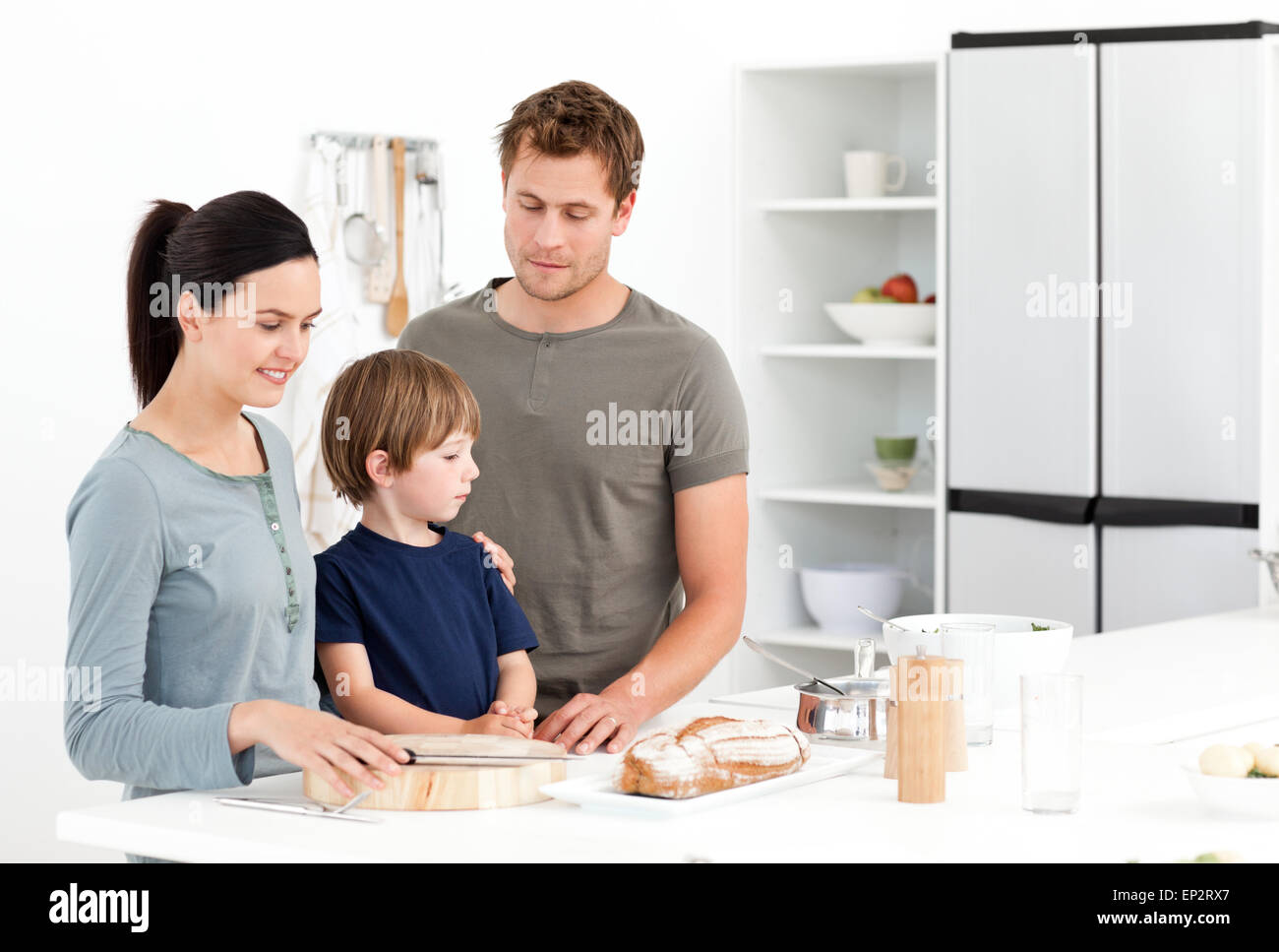 Happy family eating bread in the kitchen Stock Photo - Alamy