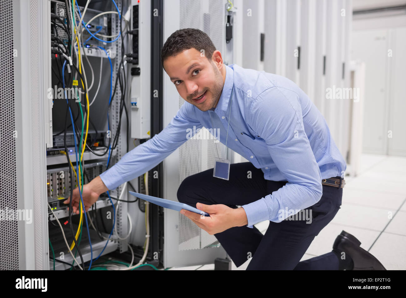 Smiling technician with tablet pc plugging cables into server Stock ...