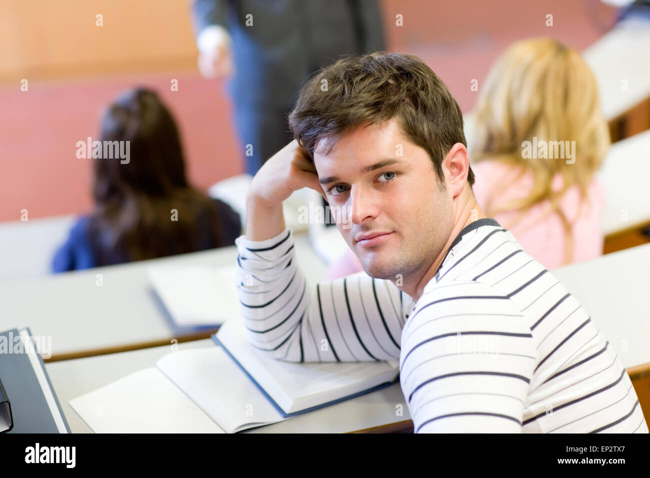 Handsome male student smiling at the camera during an university lesson ...