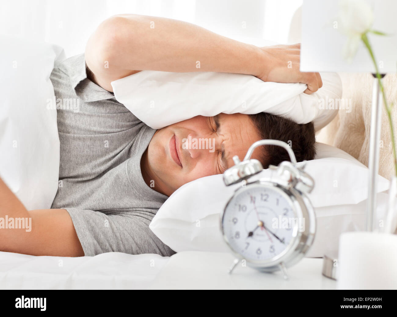 Frustrated man listening to his alarm clock Stock Photo - Alamy
