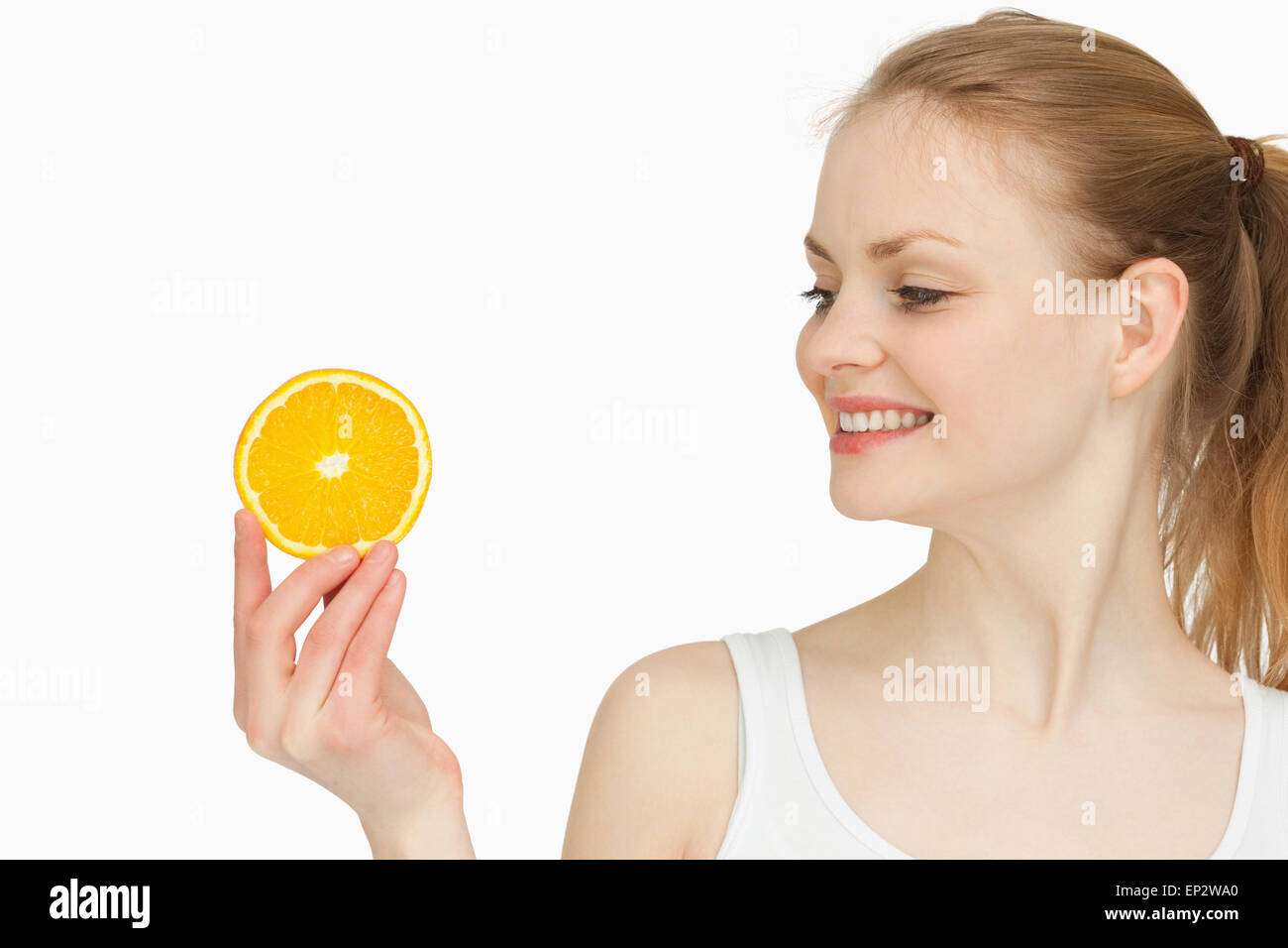Woman presenting an orange slice while looking at it Stock Photo - Alamy