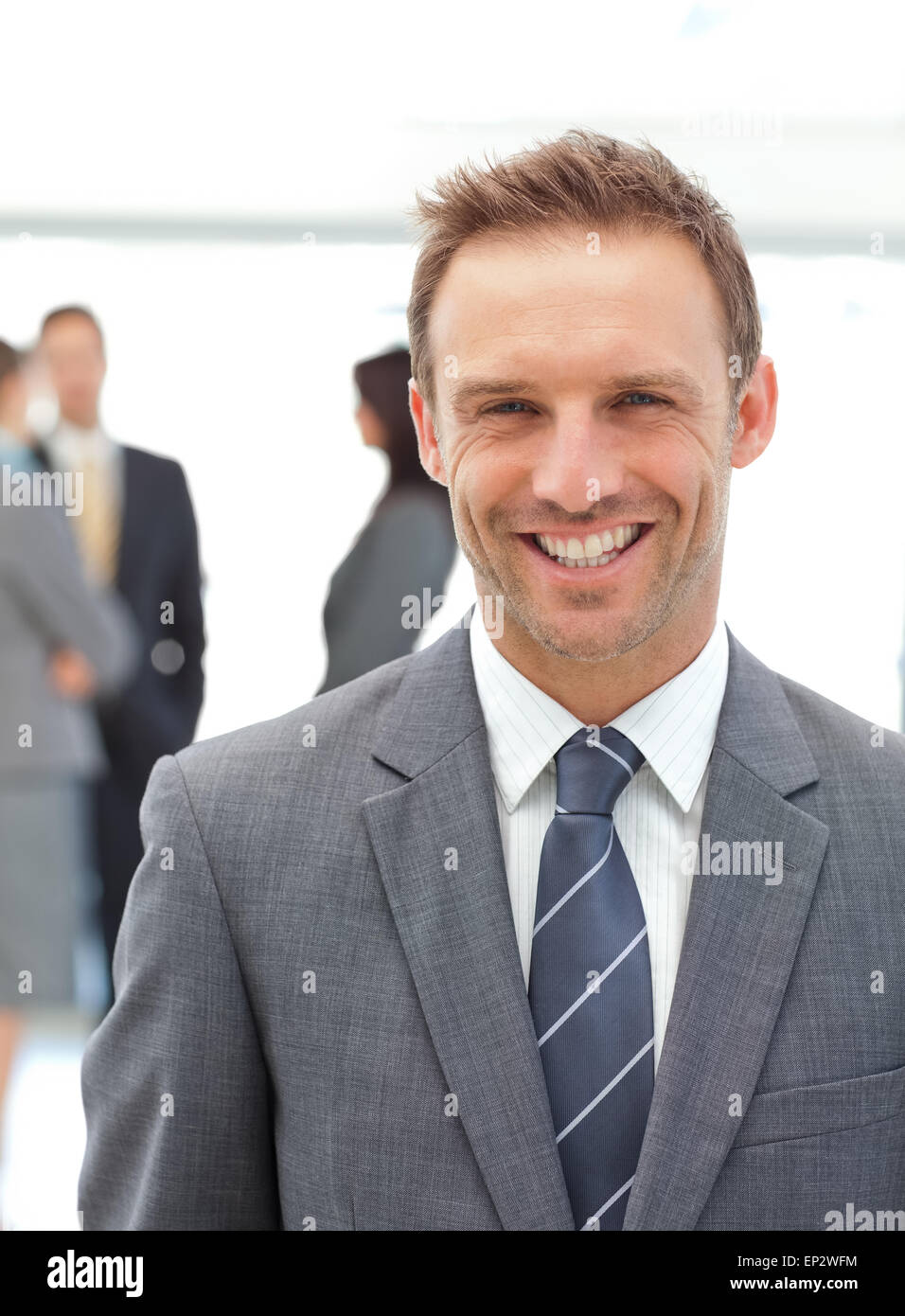 Happy manager standing in front of his team Stock Photo - Alamy