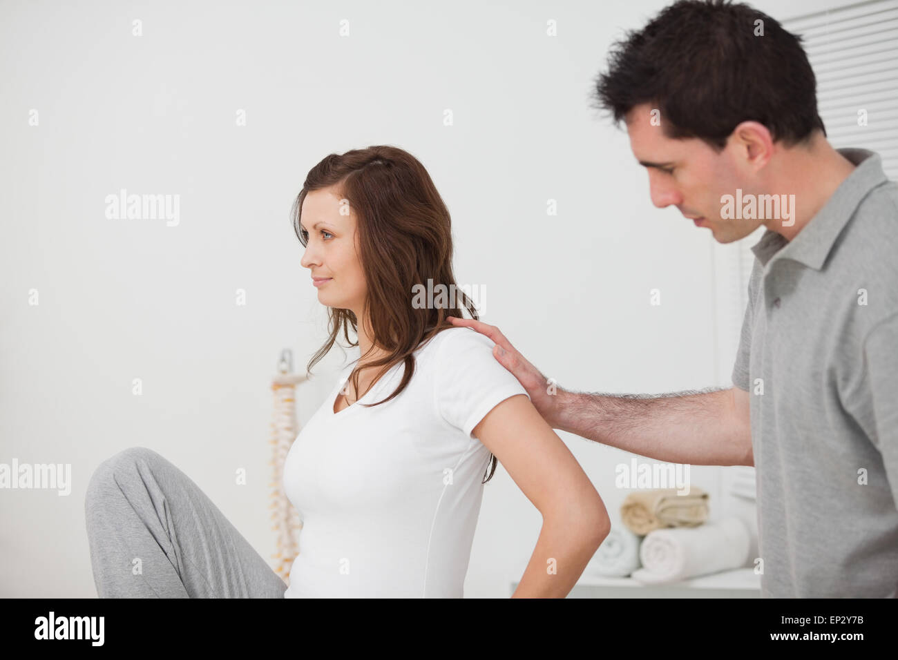 Woman sitting while a man is touching her back Stock Photo - Alamy