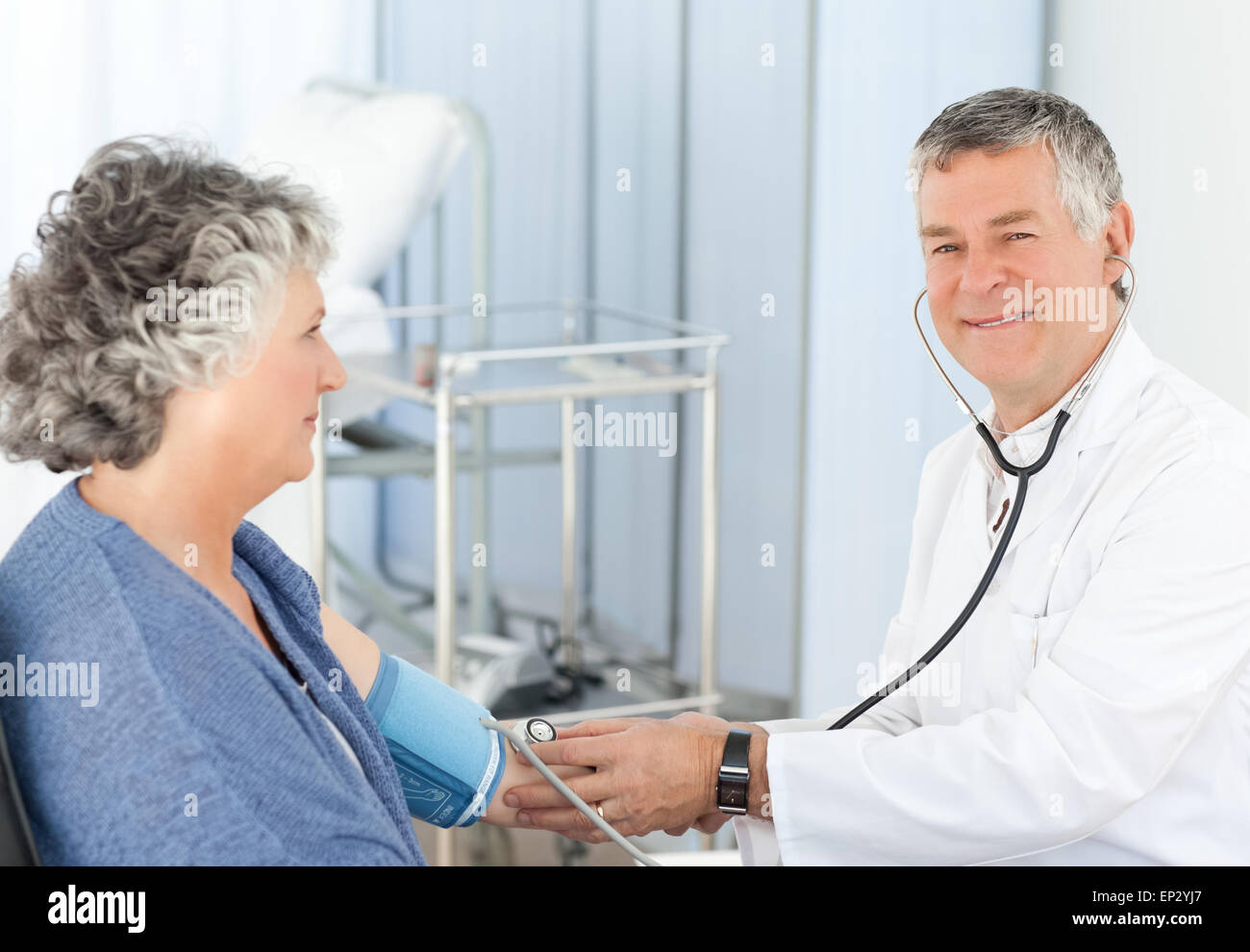 A senior doctor taking the blood pressure of his patient Stock Photo ...